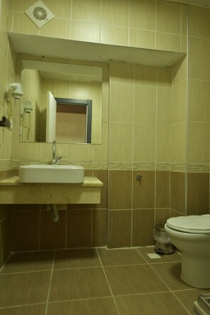 Casa de banho com lavatório, espelho, sanita e paredes em azulejo.