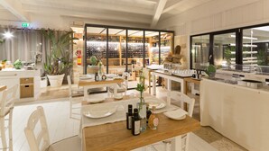 Restaurante com mobiliário branco, uma mesa de madeira e vista para a adega.