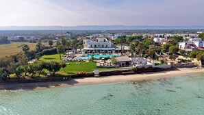 Um resort costeiro com piscina, praia e vegetação ao redor.