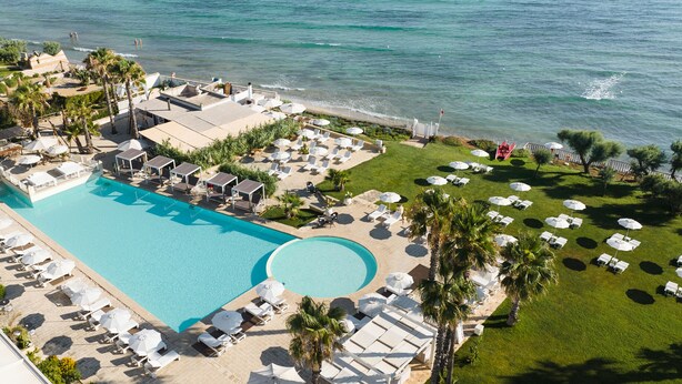 Vista aérea de um resort com uma piscina grande, espreguiçadeiras e uma área de praia.