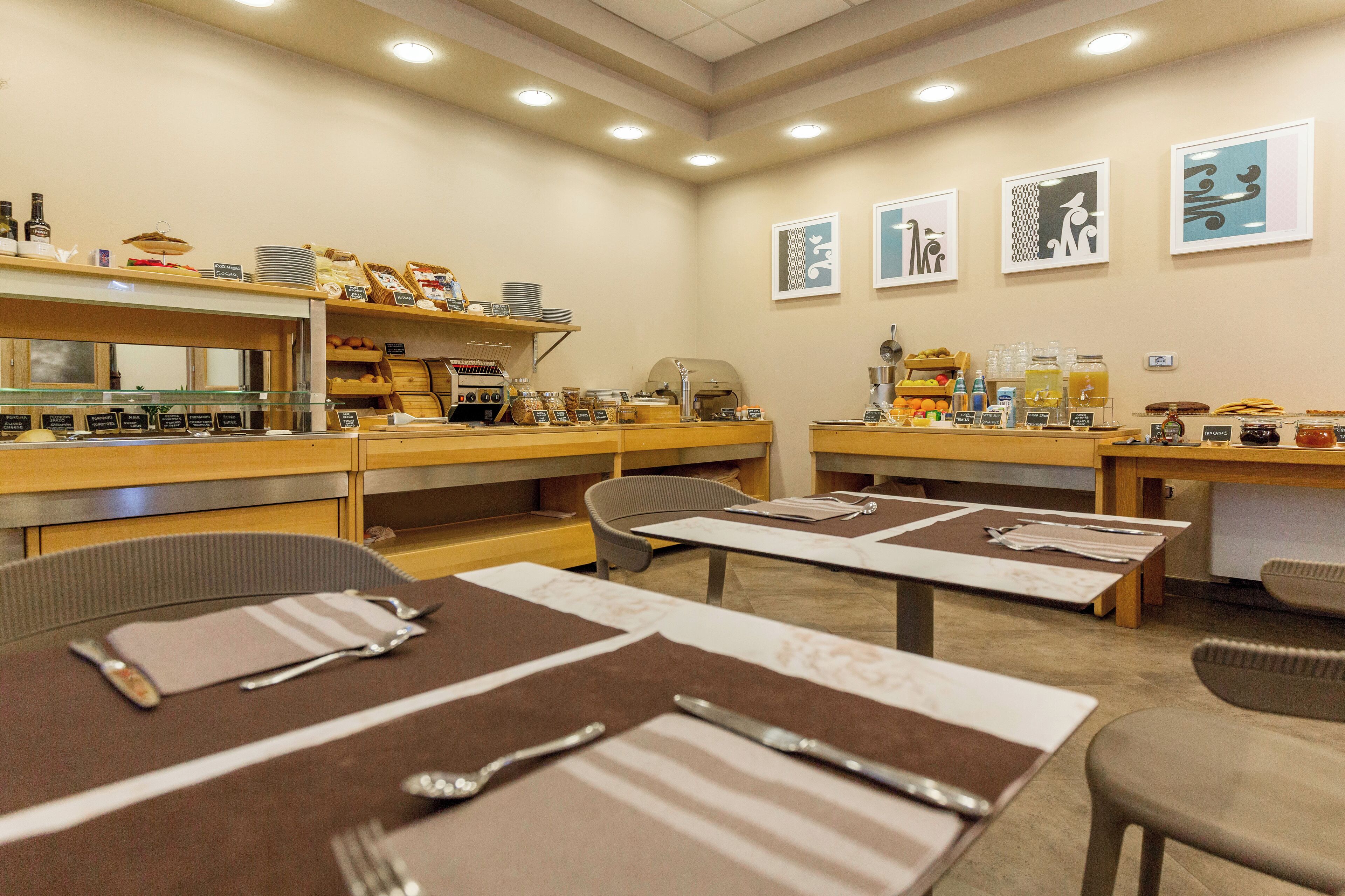 Uma área de refeições com mesas preparadas para as refeições, um espaço para café e diversos alimentos expostos em prateleiras.