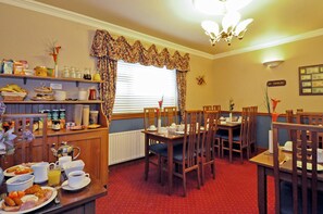 Espaço de café da manhã com serviço de buffet, incluindo diversos alimentos e bebidas.