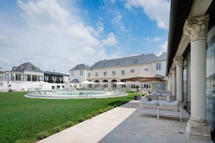 Um pátio com piscina, área de estar externa e um edifício grande com arquitetura clássica.
