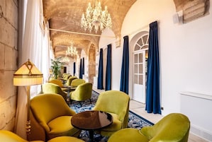 Um saguão de hotel com cadeiras amarelas, um candelabro e um tapete azul.