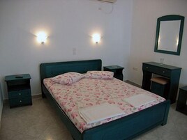 Quarto com cama, mesas de cabeceira, cômoda e espelho.