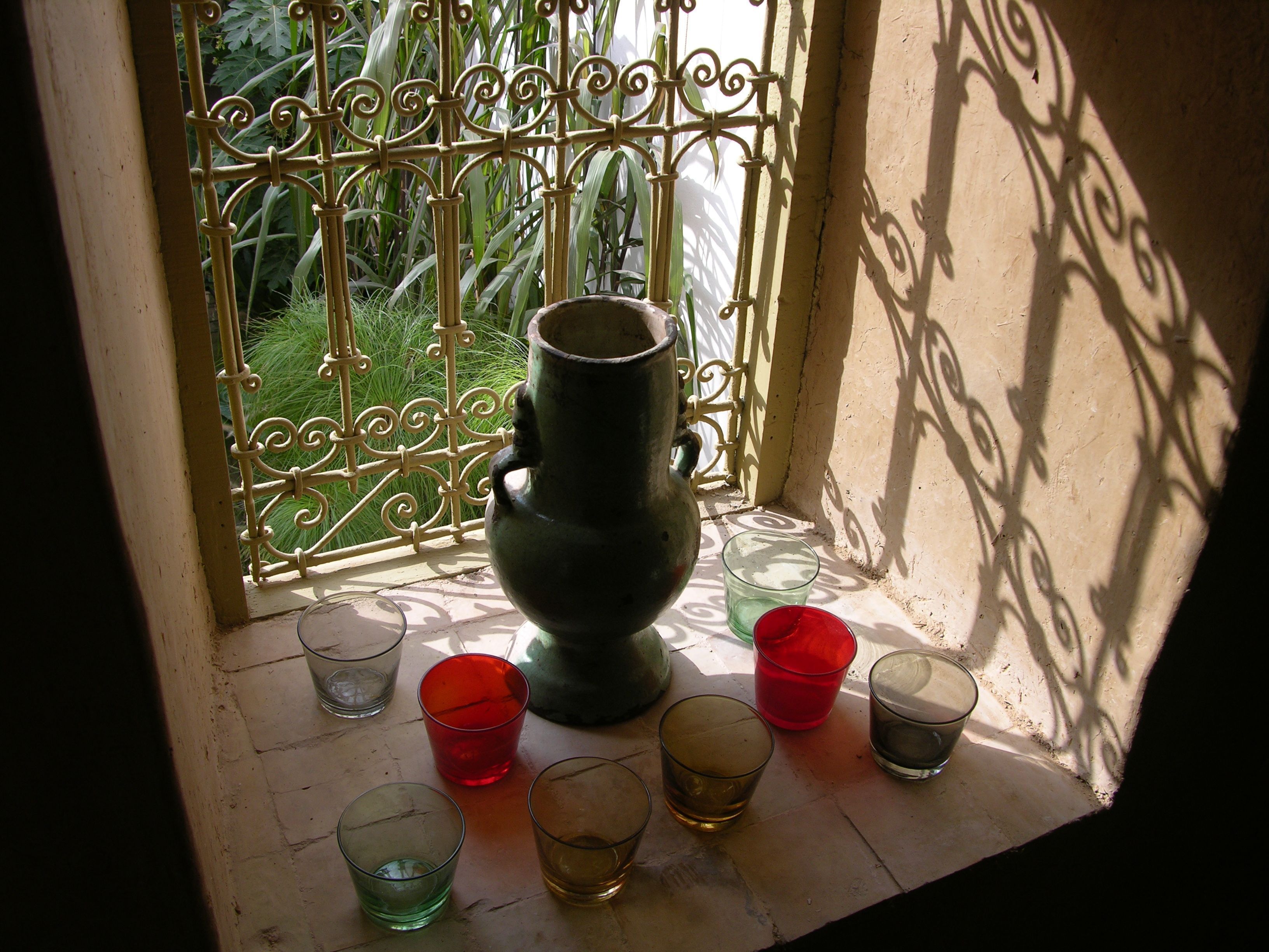 Janela com grade de metal decorativa e planta em vaso ao fundo.