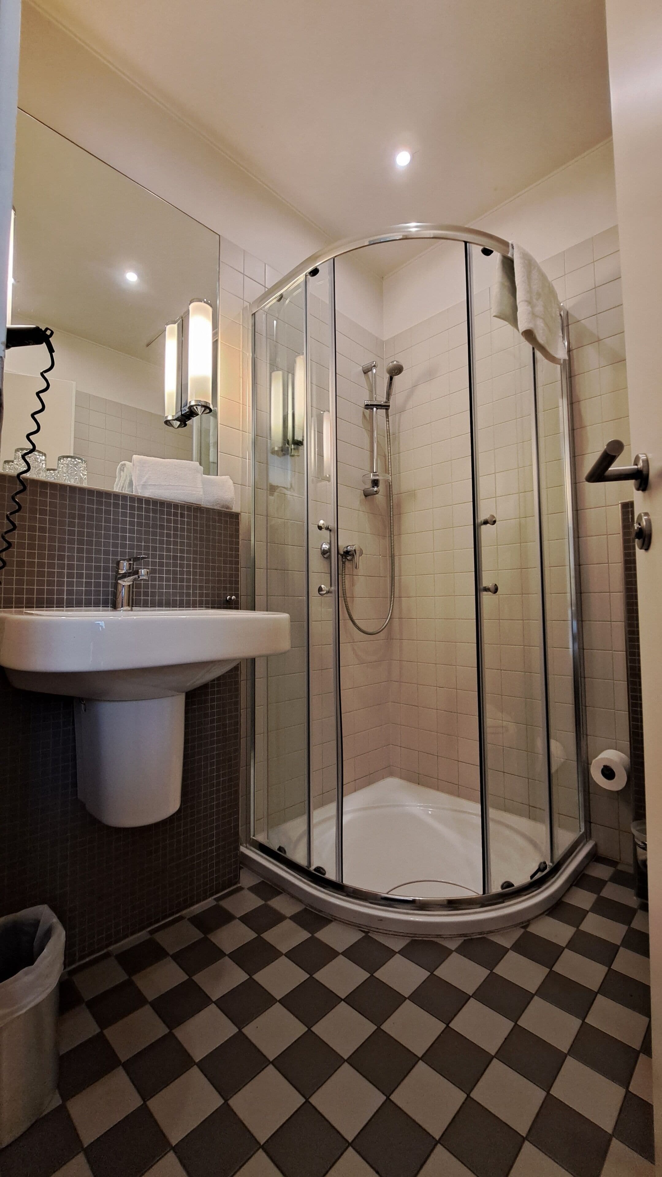 Uma casa de banho moderna com cabine de duche em vidro, lavatório e espelho.