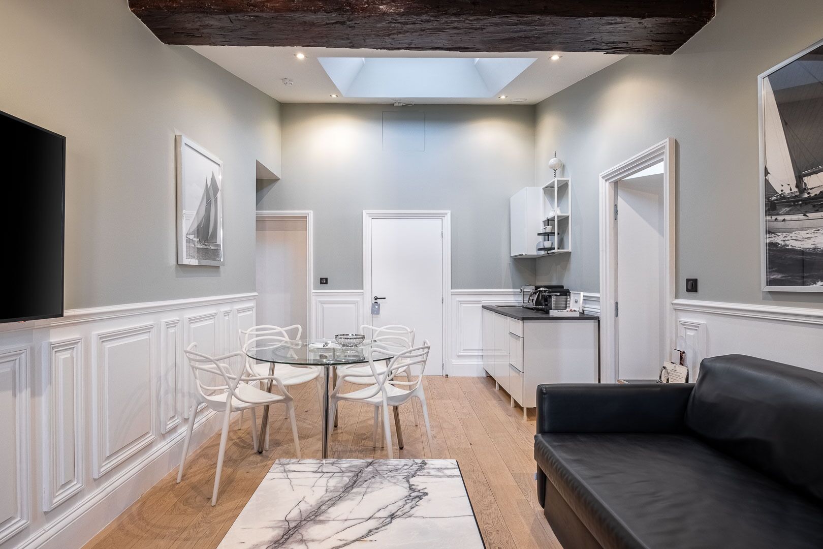 Um espaço compacto com área de refeições, pequeno espaço de cozinha e sofá preto.