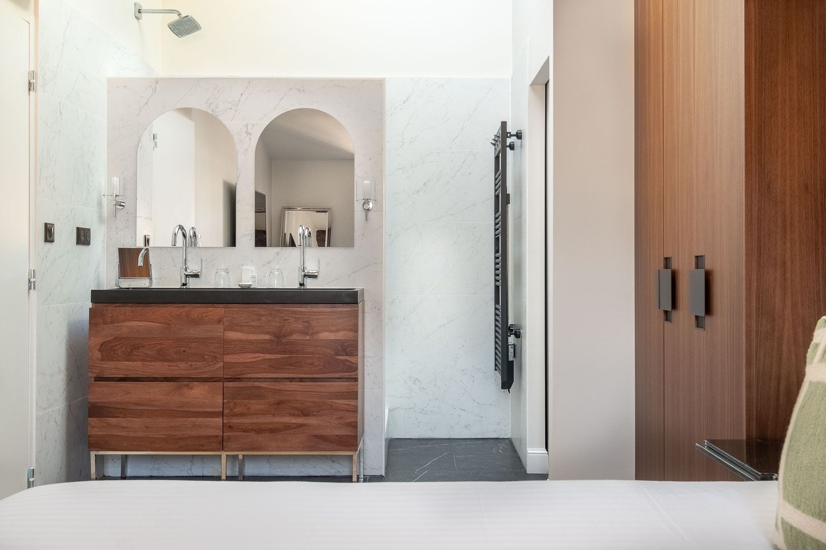 Uma casa de banho moderna com lavatório de mármore, chuveiro e porta de madeira.