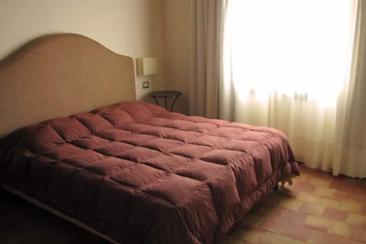 Uma cama de solteiro com cabeceira, mesa de cabeceira e luminária.
