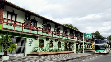 Um hotel com fachada verde, várias varandas e uma placa indicando ser um hotel.