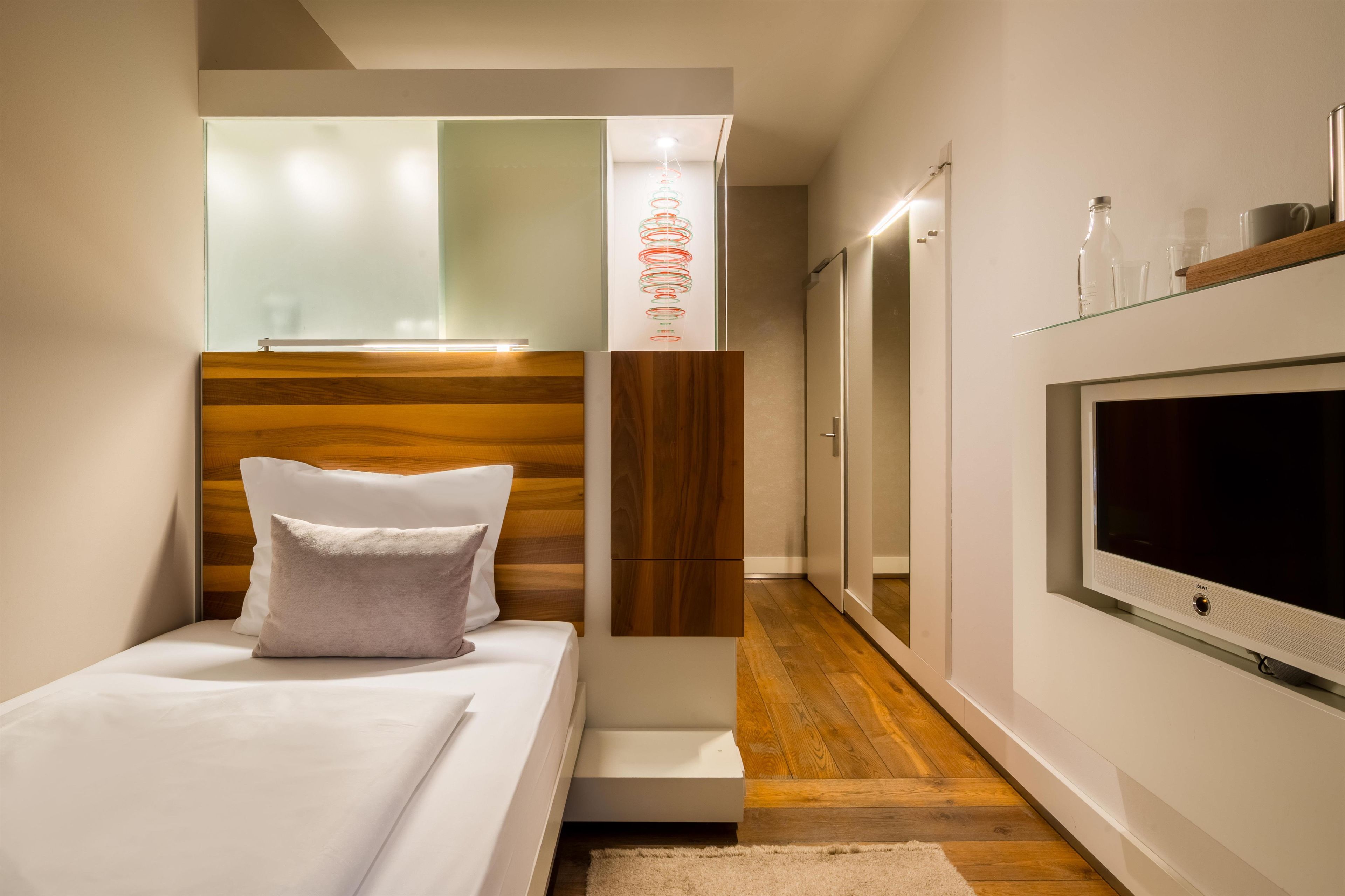 Quarto moderno com cama, televisão e cabeceira de madeira.