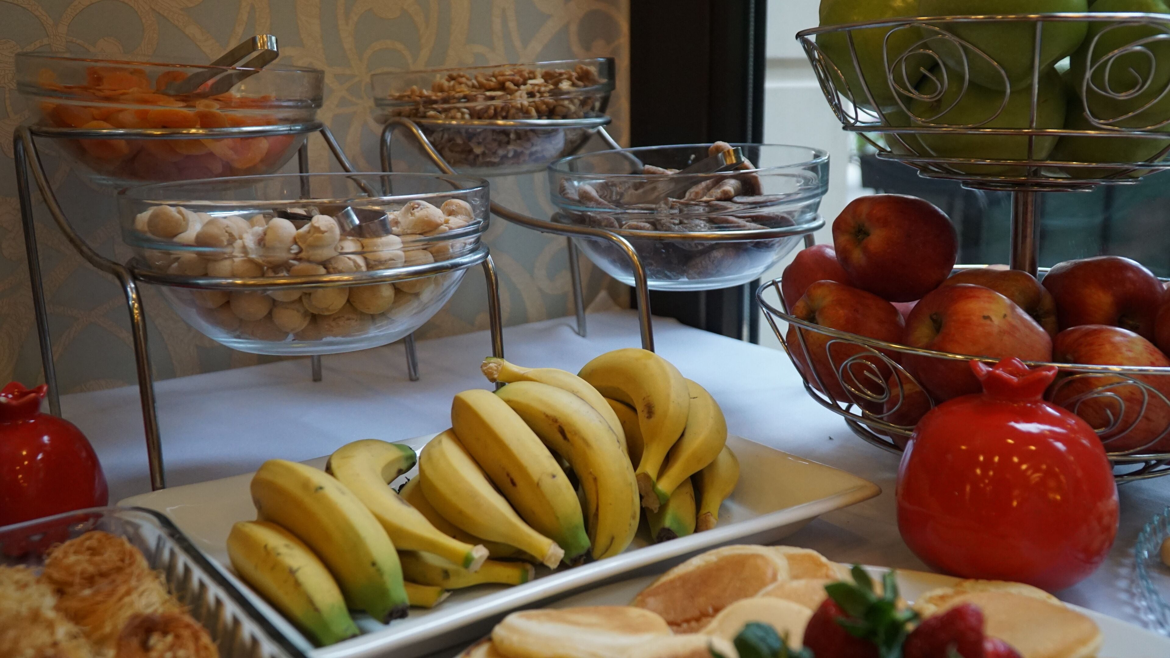Buffet com diversas opções de comida, incluindo bananas, maçãs e nozes.