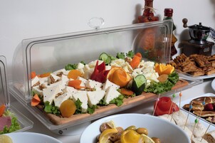 Buffet com diversos alimentos, incluindo queijo, frutas e legumes.