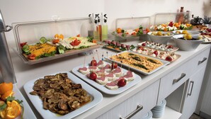 Buffet com diversas opções de comida, incluindo saladas, carnes e petiscos.