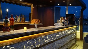 Uma área de bar com bancada de mármore, uma vela e várias garrafas.