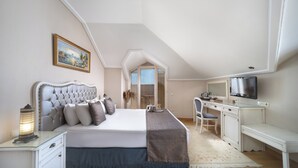 Quarto com uma cama grande, escrivaninha, televisão e janela com vista.