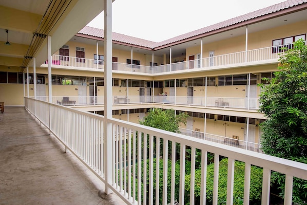 Hotel com vários andares, varandas, galeria coberta e um pátio com vegetação.