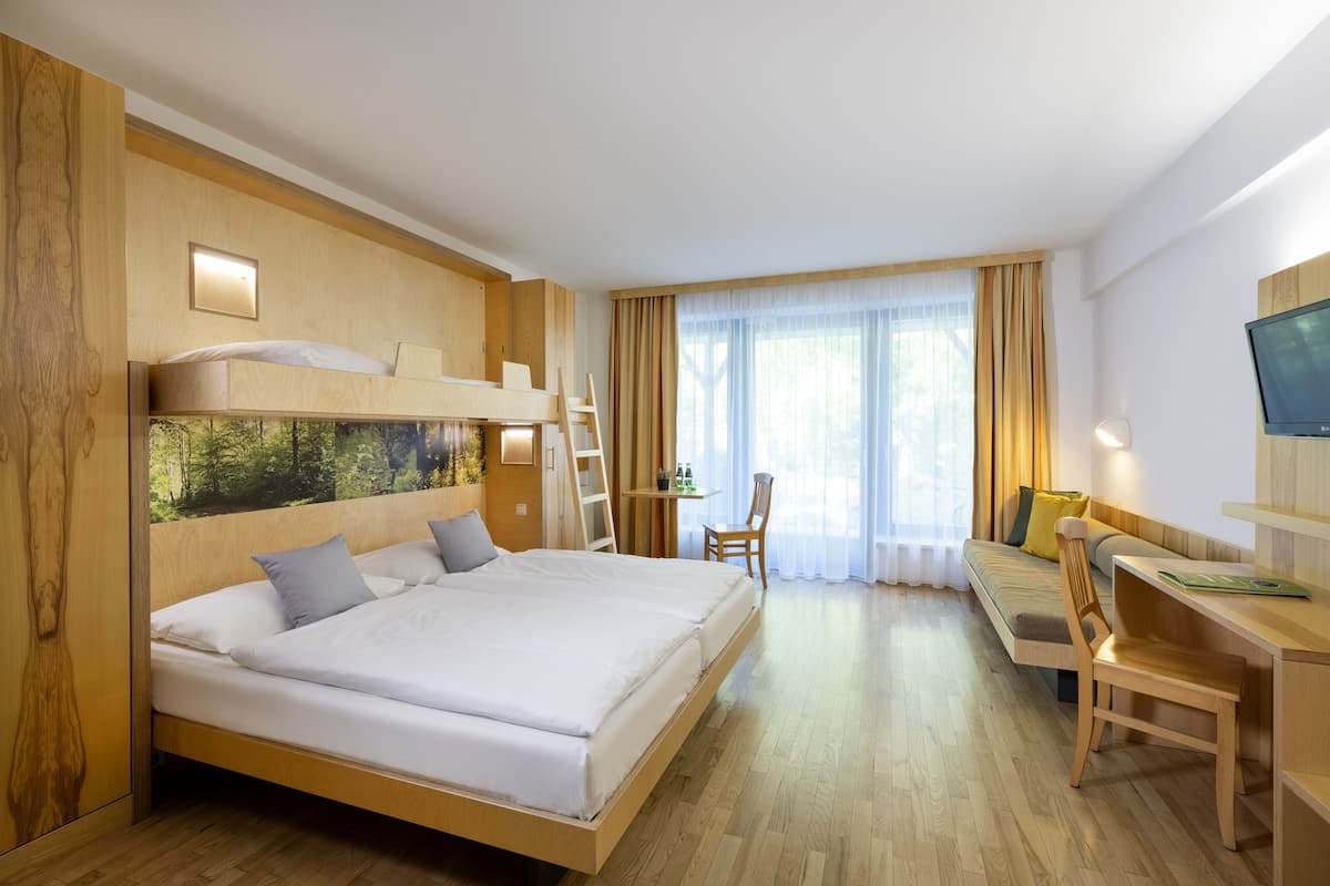 Quarto de hotel moderno com uma cama grande, uma escrivaninha e uma televisão.