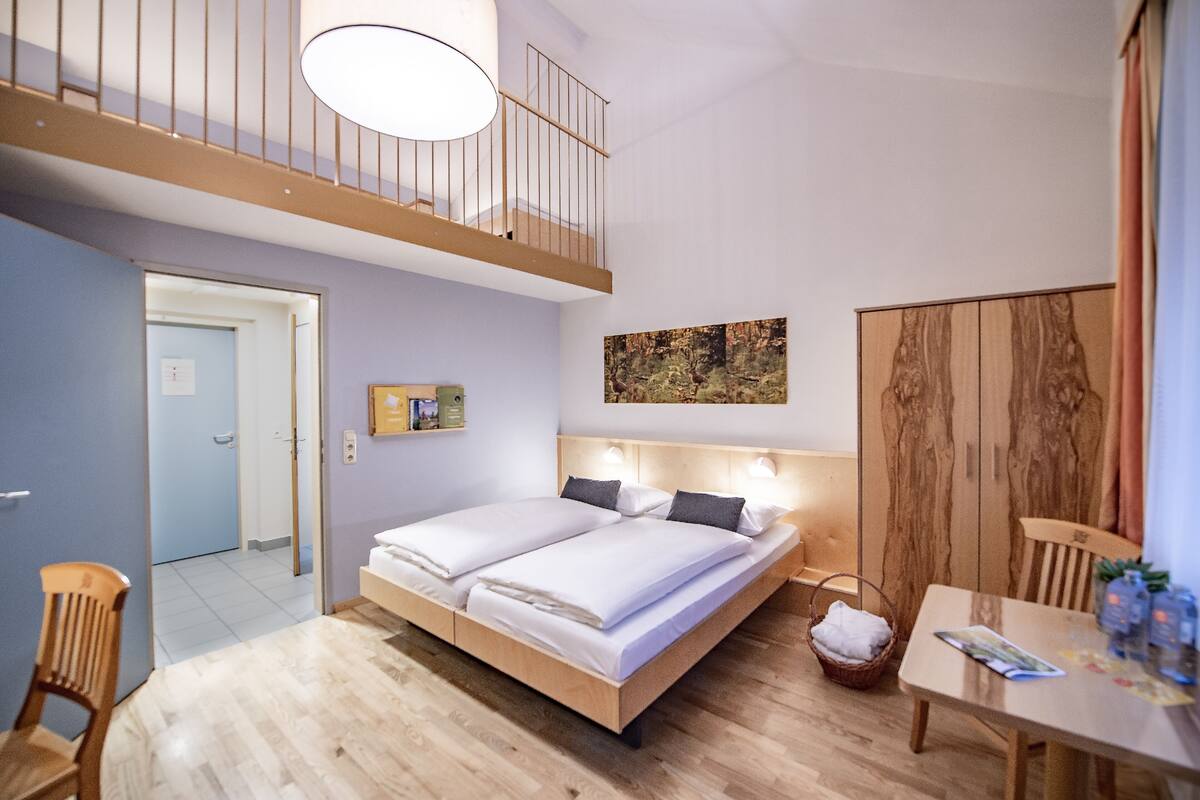 Quarto de hotel moderno com uma cama grande, uma escrivaninha de madeira e uma varanda.