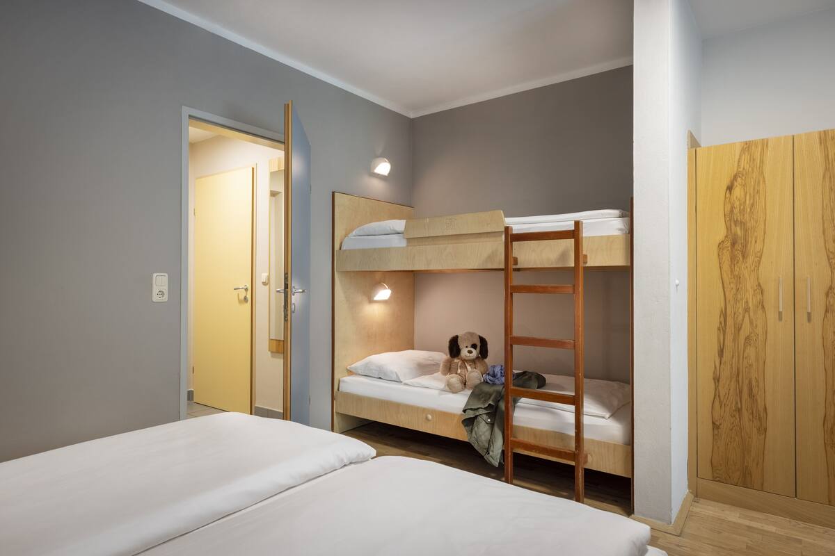 Quarto com beliche, uma escrivaninha pequena e um guarda-roupa.