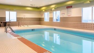 Piscina interna com regras claras afixadas na parede, incluindo horário de funcionamento e ausência de salva-vidas.