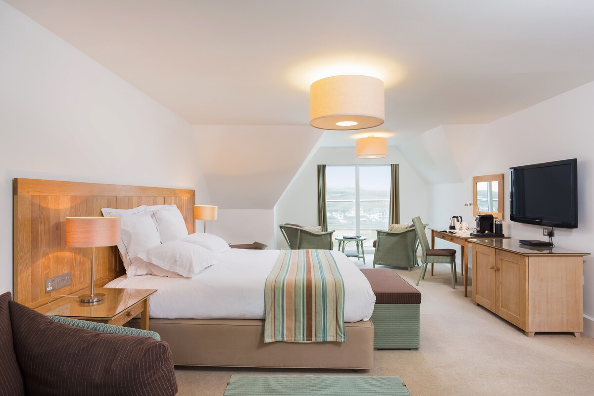 Quarto de hotel com cama, secretária, televisão e vista para a cidade.