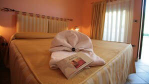 Quarto de hotel com uma cama, janela com cortinas, ar condicionado e uma toalha com um folheto.