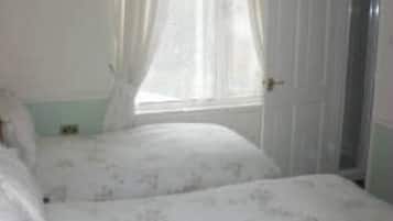 Quarto com duas camas, uma janela com cortinas leves e uma porta.