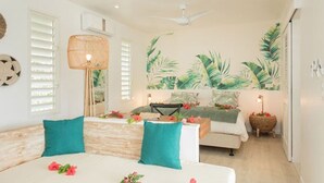 Quarto com cama, sofá, ventilador de teto e parede com um mural tropical.