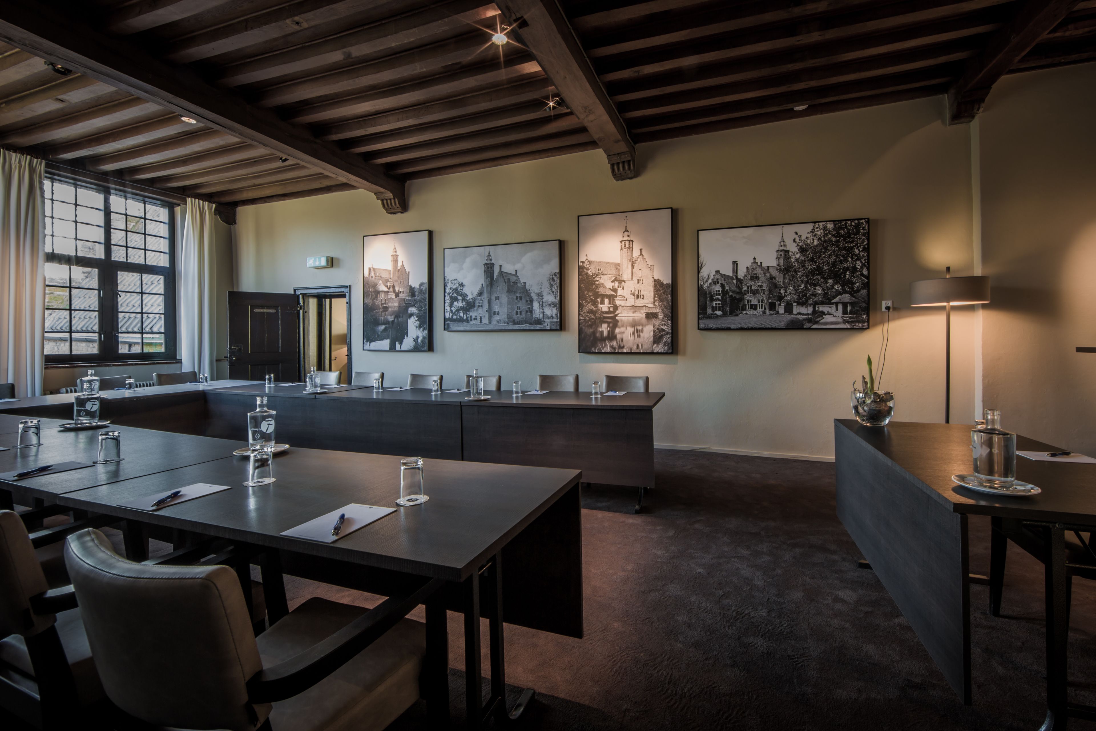 Uma sala de conferências com uma mesa comprida, cadeiras e teto de madeira escura.