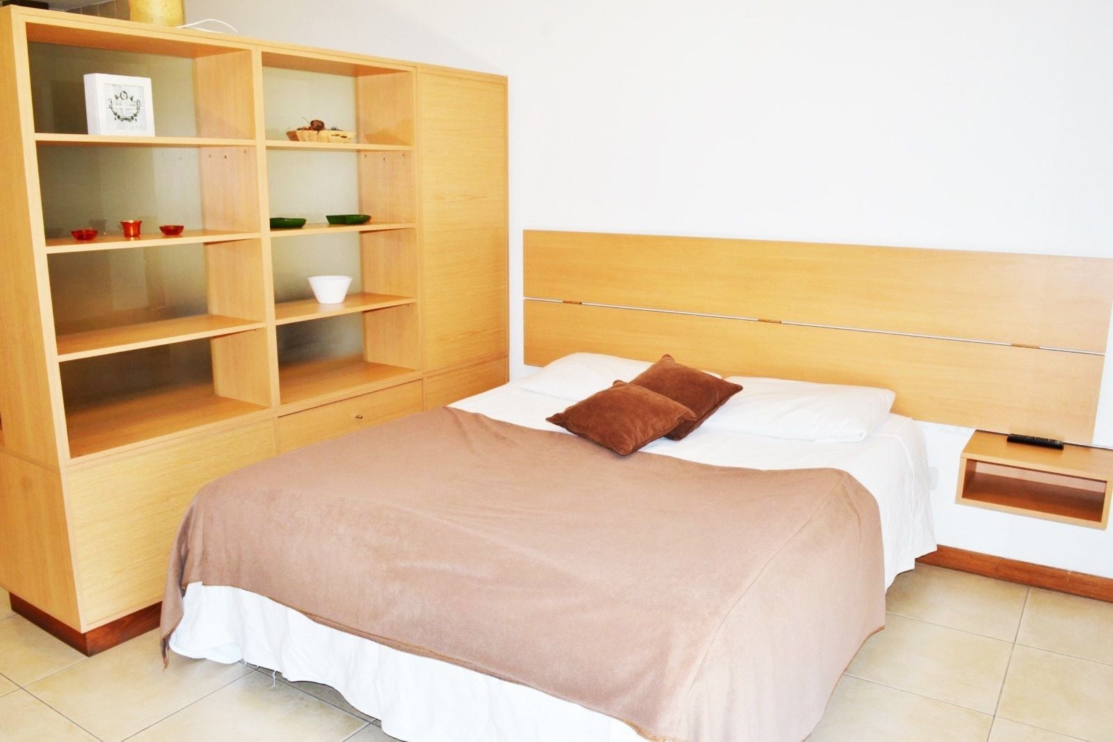 Quarto com cama, guarda-roupa de madeira e mesa de cabeceira.