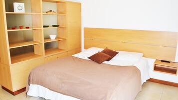 Quarto com cama, guarda-roupa de madeira e mesa de cabeceira.