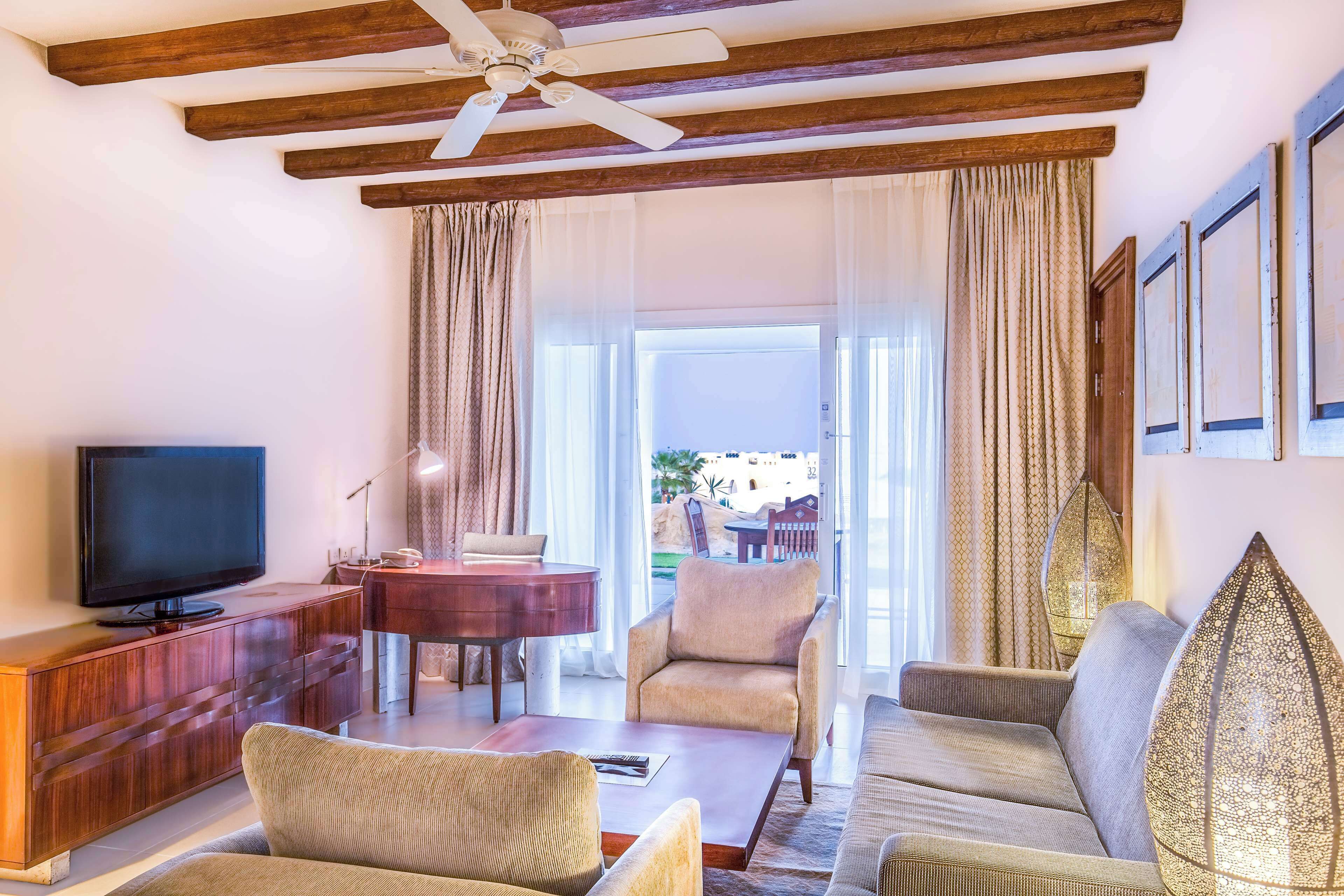 Sala de estar com televisão, sofá, poltrona e mesa de jantar.