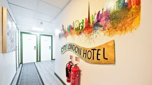 Corredor com portas identificadas com os números 334 e 335, um extintor de incêndio e uma placa na parede com a inscrição "City London Hotel".