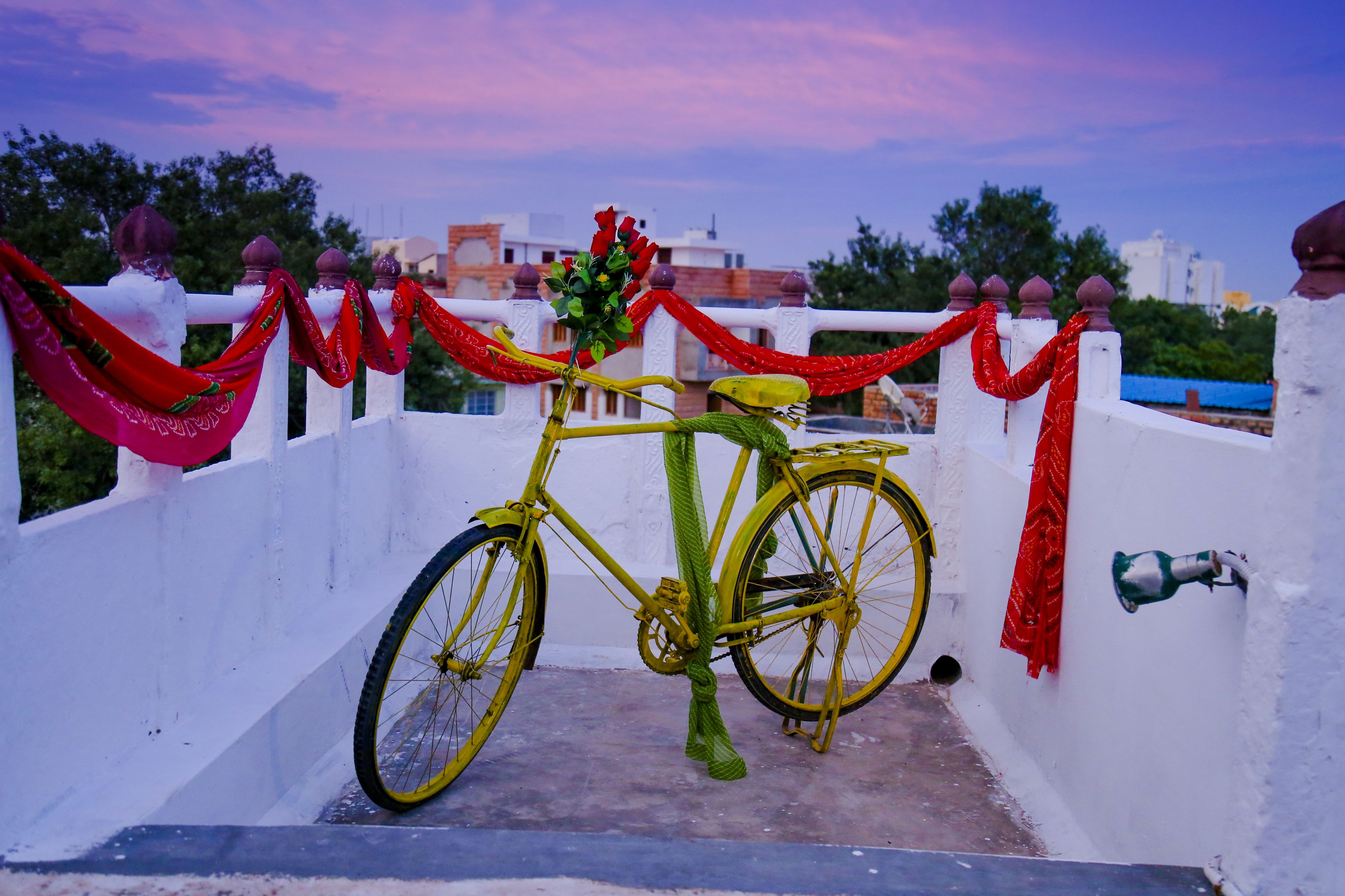 Uma bicicleta amarela estacionada numa varanda com decorações vermelhas e cor-de-rosa.