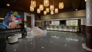 Um lobby moderno com área de bar, escadaria e um mural na parede.