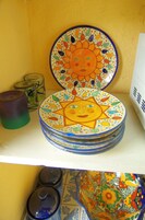 Uma prateleira com pratos decorativos, uma vela e um recipiente de vidro.