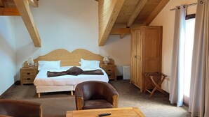 Quarto com teto de madeira, uma cama, uma escrivaninha e duas cadeiras.