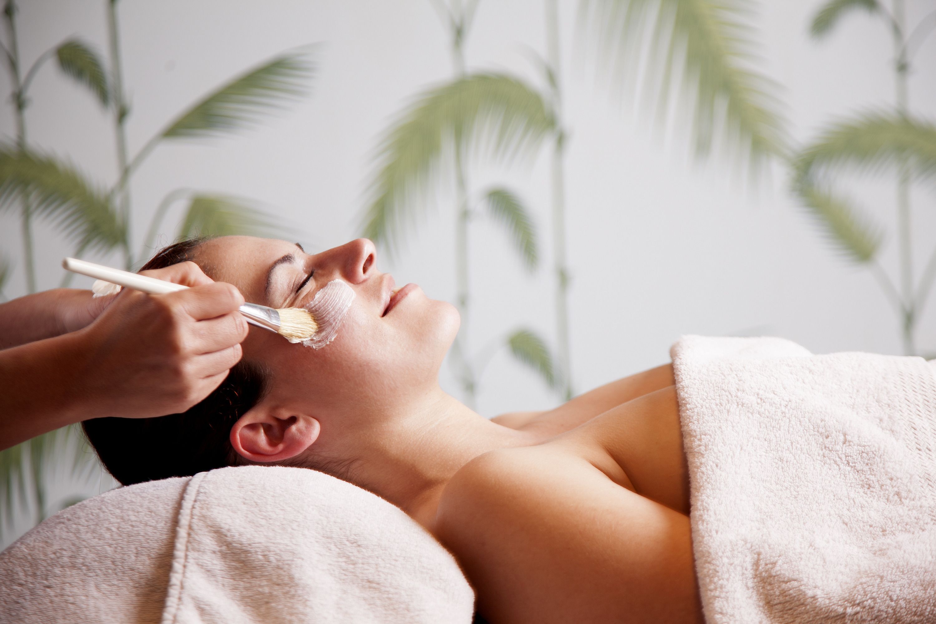 Uma pessoa recebendo tratamento facial com uma toalha nos ombros.