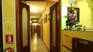 Um corredor de hotel com um extintor, uma árvore de Natal e uma receção.