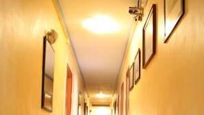 Um corredor de hotel com piso de azulejos, quadros nas paredes e portas de acesso aos quartos.