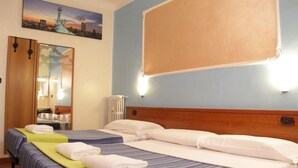 Quarto de hotel com duas camas, um espelho grande, uma pintura da Estátua da Liberdade e uma janela com vista para o horizonte da cidade.