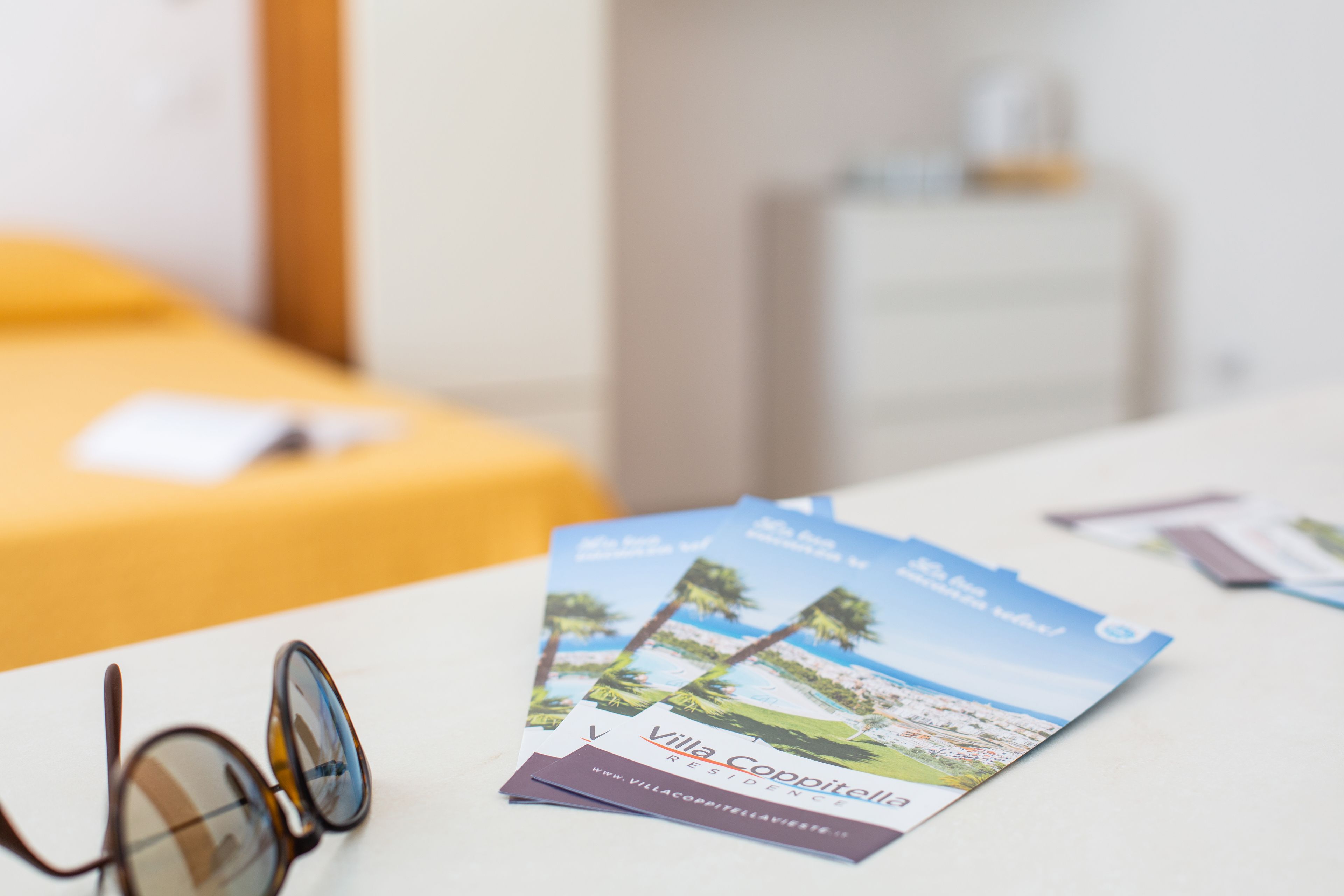 Um folheto intitulado 'Villa Coppitella' sobre uma mesa, com um par de óculos ao lado.