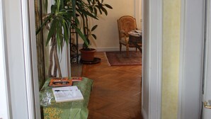 Um corredor com piso de madeira, uma mesa de jantar com toalha verde e um vaso de planta.