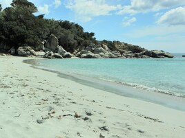 Perto da praia, areia branca, espreguiçadeiras, guarda-sóis 