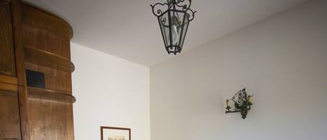 Quarto com cama, guarda-roupa de madeira, televisão, mesa de cabeceira e luminária na parede.
