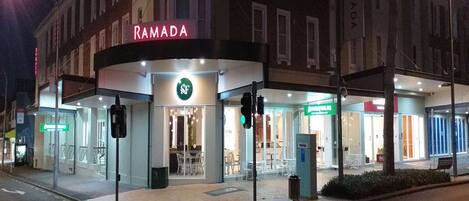 Um edifício com uma placa indicando "RAMADA" e uma placa verde que sinaliza um restaurante.