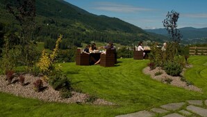 Um grupo de pessoas jantando ao ar livre com uma paisagem montanhosa ao fundo.