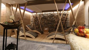 Um espaço de spa com cadeiras de madeira, uma parede de pedra e uma cesta de frutas.